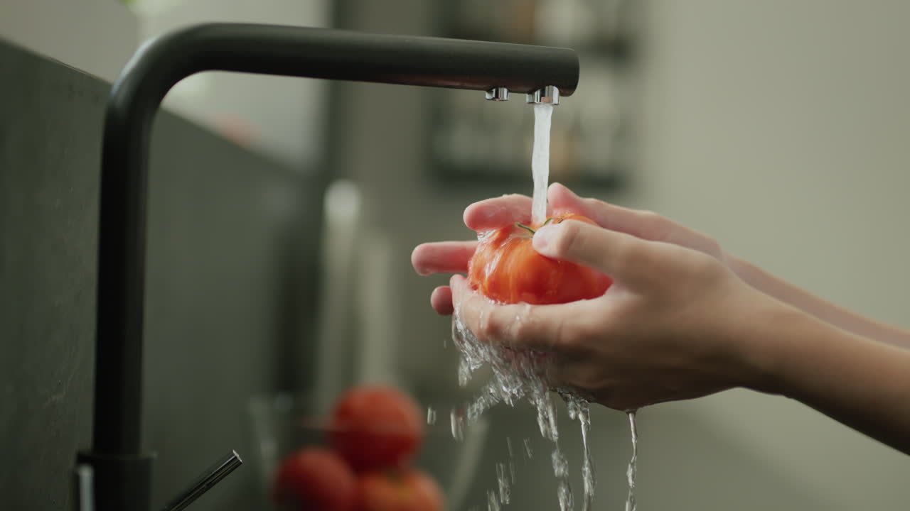 Premium stock video - Juicy red tomato is washed under water from the ...