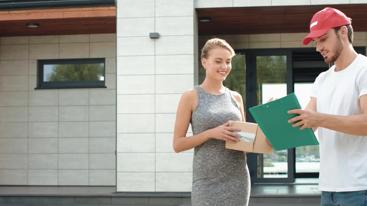 Premium stock video - Postman delivering box to blonde woman. beautiful ...