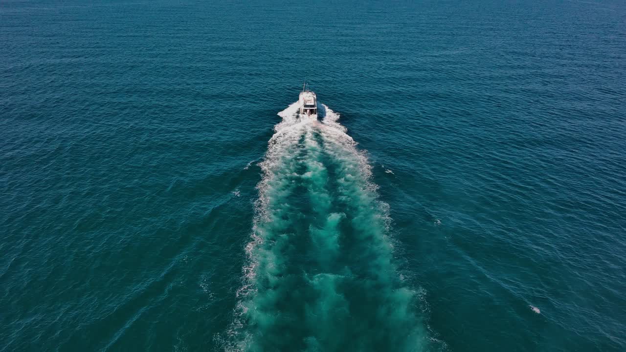 Long white wake trail of speedboat cruising over calm blue sea water ...