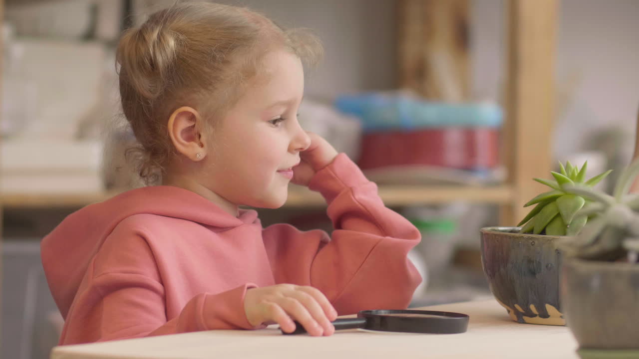 Little Girl Observing A Plant On A Table Where Is A Magnifying Glass In ...