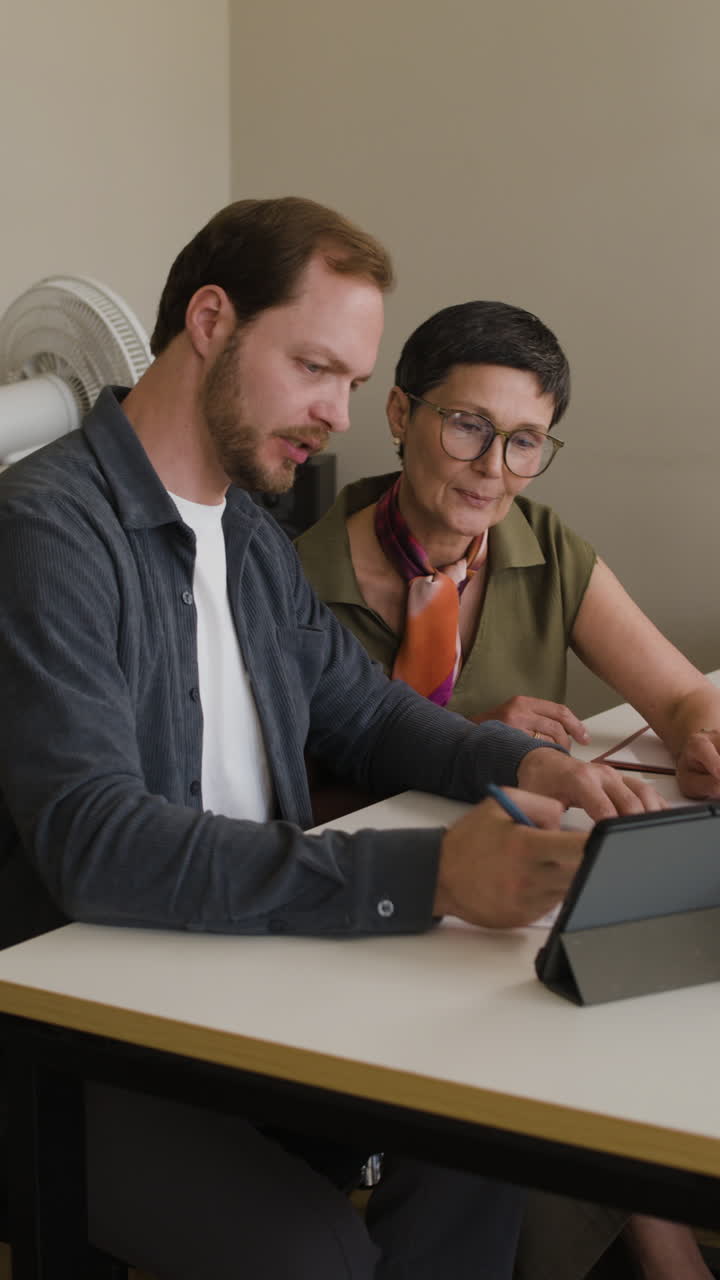 Two people collaborating and working together at a desk with a tablet ...