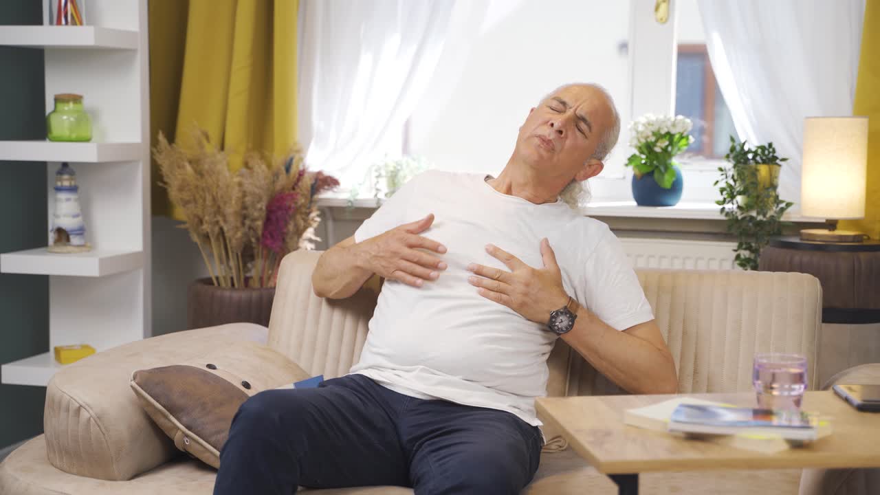 Premium stock video - Old man with shortness of breath is breathing hard.