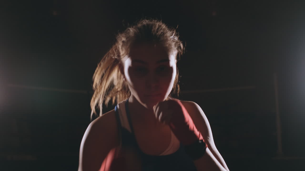 Premium stock video - A beautiful female boxer strikes directly into ...