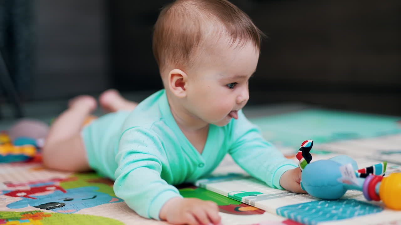 Playful kid lying on belly and waving his toy. Beautiful baby showing ...