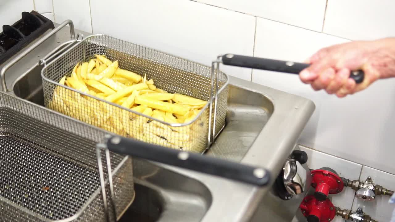 Person Frying Cut Potatoes In The Oil Of A Deep Fryer In Slow Motion In ...