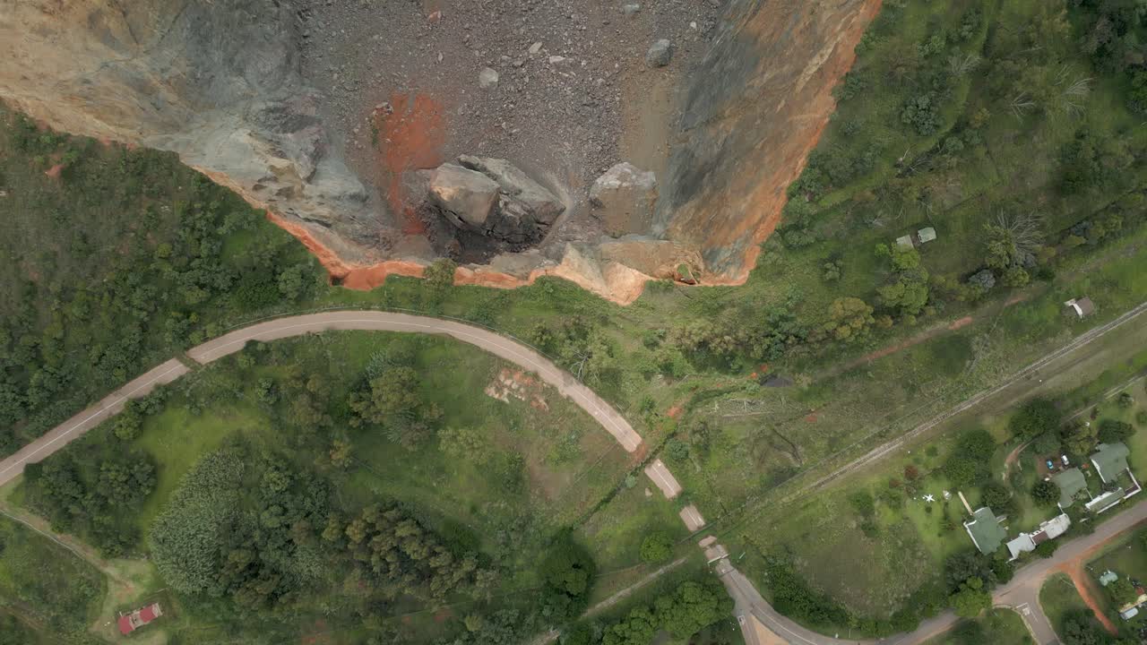 Aerial: Precipitous edge of open pit mine growing close to closed road ...