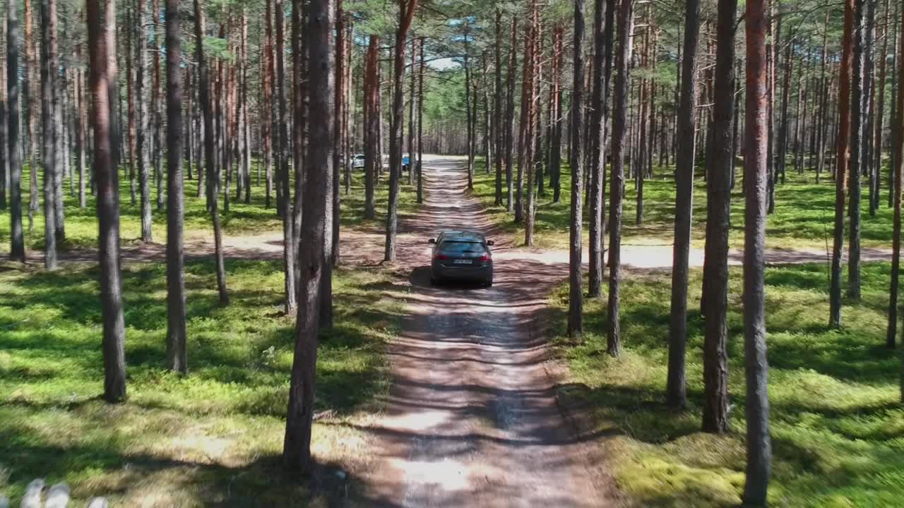 Premium stock video - An aerial shot following a car between trees