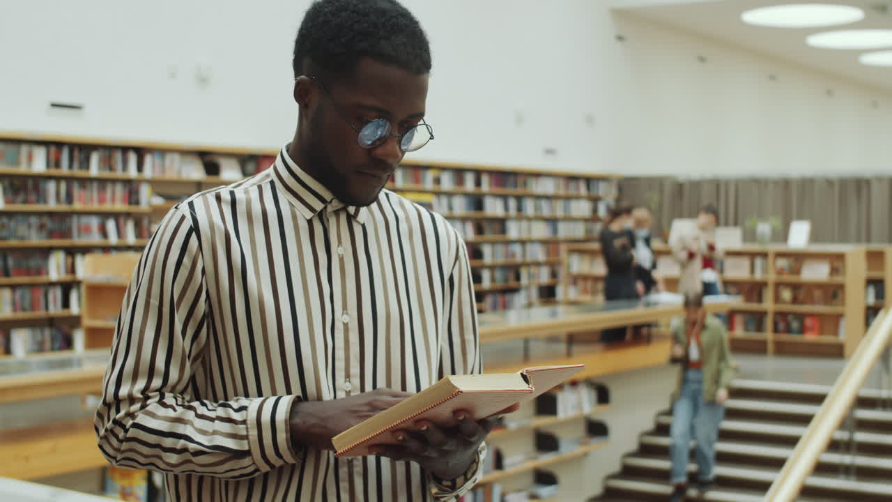 African man reading book in library Premium Stock Video Footage