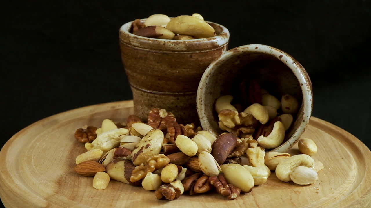 Cashews, walnuts, pistachios, brazil nuts rotate on black background ...
