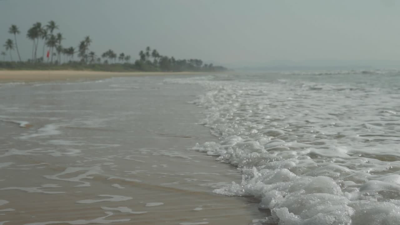 Low angle slow motion shot of benaulim beach in goa with calm waves and ...