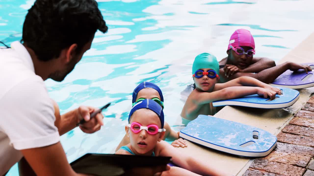 Premium stock video - Coach giving swimming lesson to his students