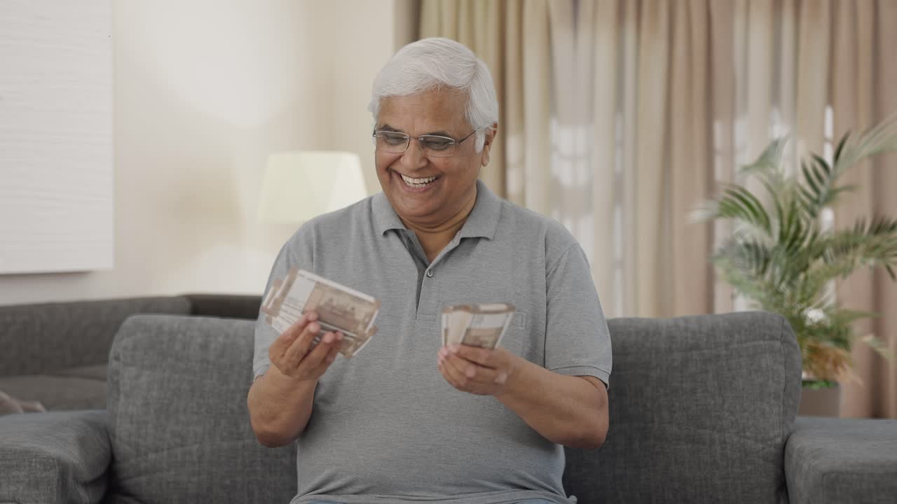 Premium stock video - Happy indian old man counting money