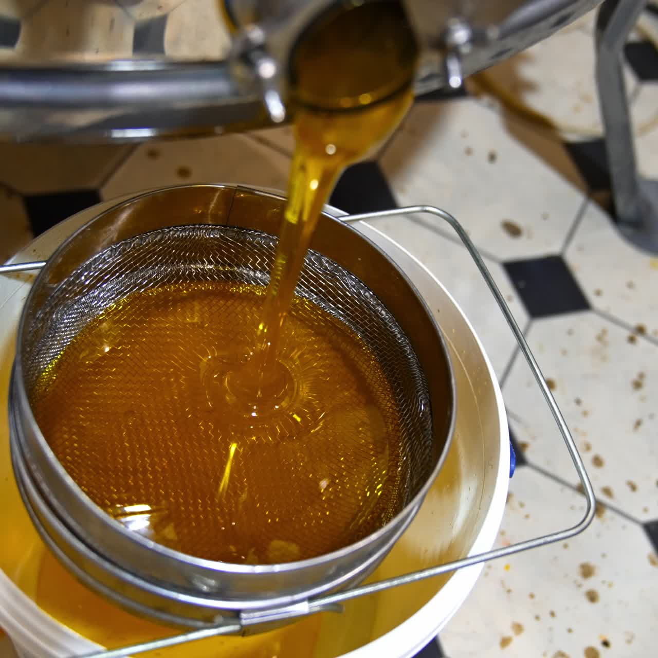 Fresh honey leaking from the faucet of honey extracting machine after ...