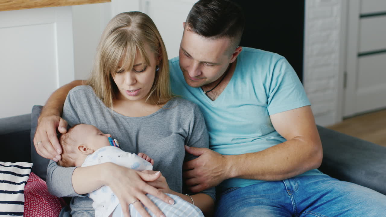 Premium stock video - Mom and dad soothe baby who cries on their hands ...