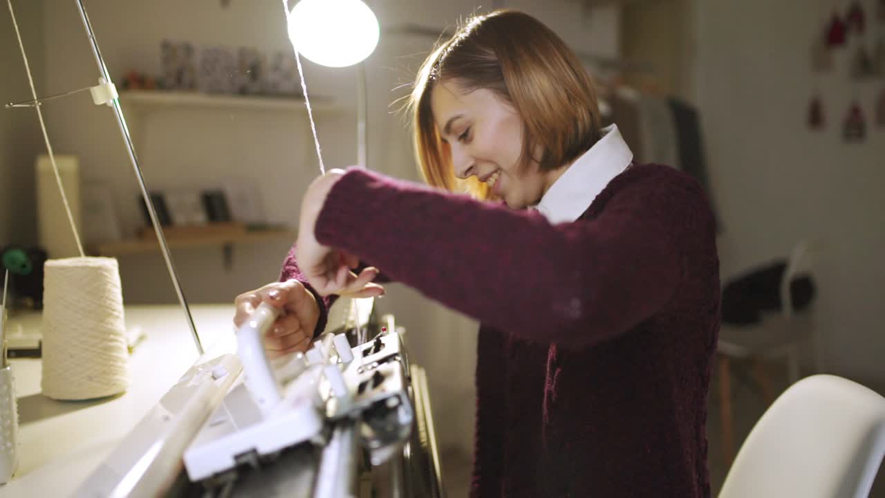 Vídeo Premium - Mujer joven tejiendo tela en una máquina de tejer en un ...