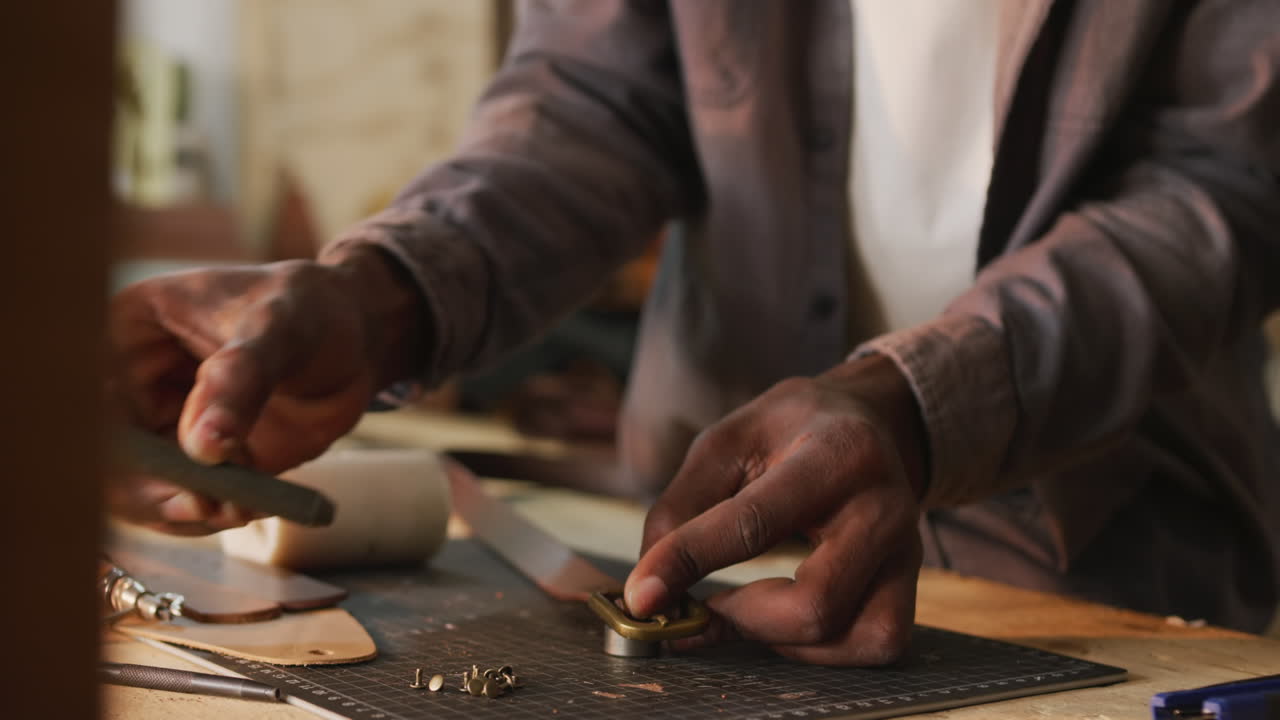 Hands of african american craftsman using tools to make a belt in ...