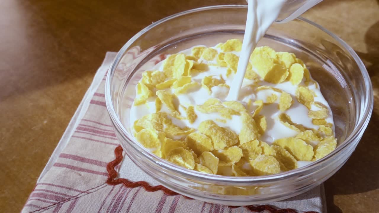 Premium stock video - Crispy yellow corn flakes into the bowl for the ...
