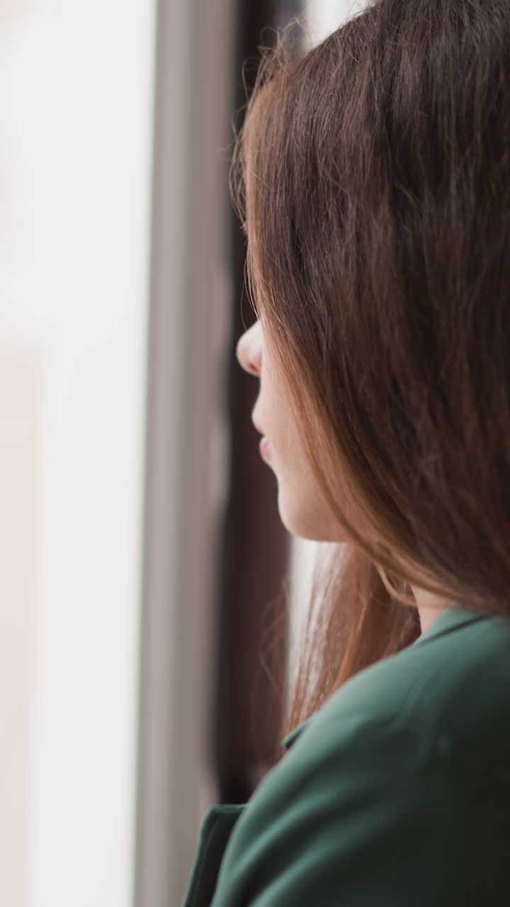 Woman looks at rain falling steadily outdoors. woman corporate worker ...