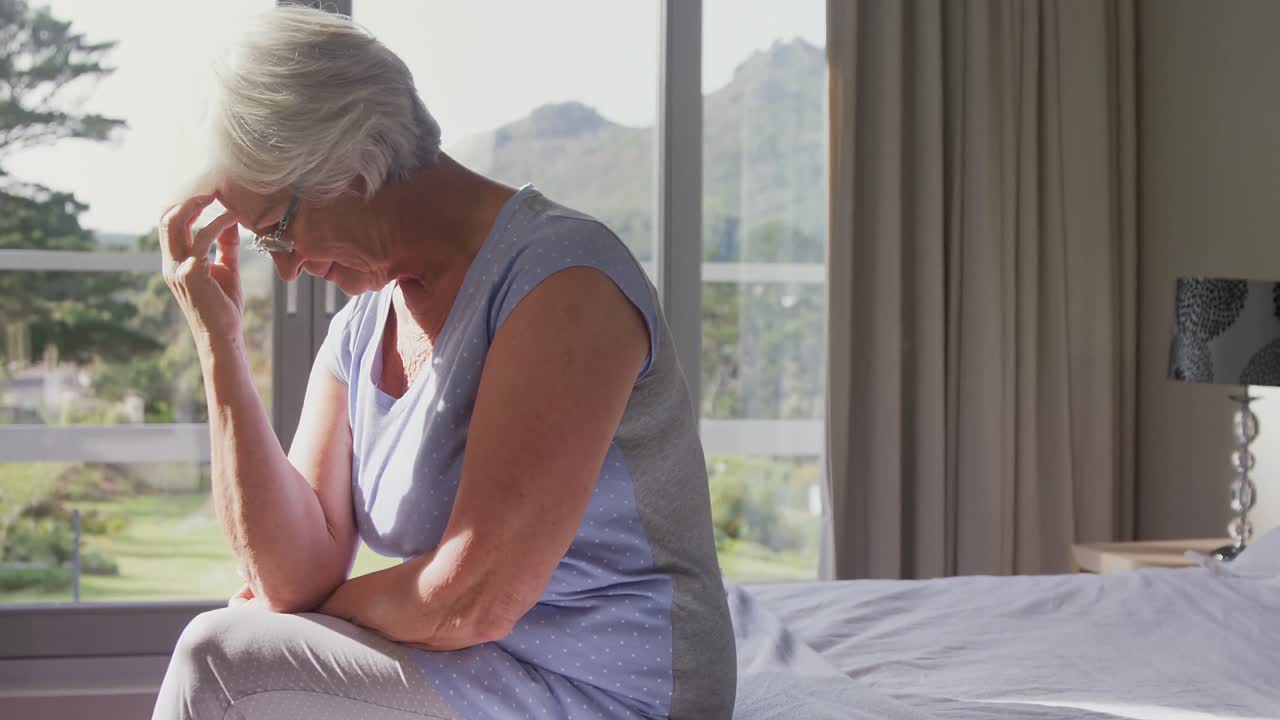 Premium stock video - Worried senior woman feeling bad seating on bed 4k 4k