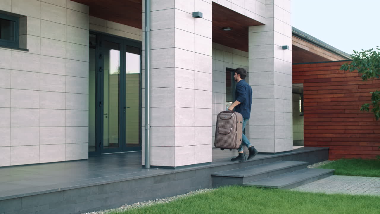 Man entering luxury apartments with suitcase. casual man coming back ...