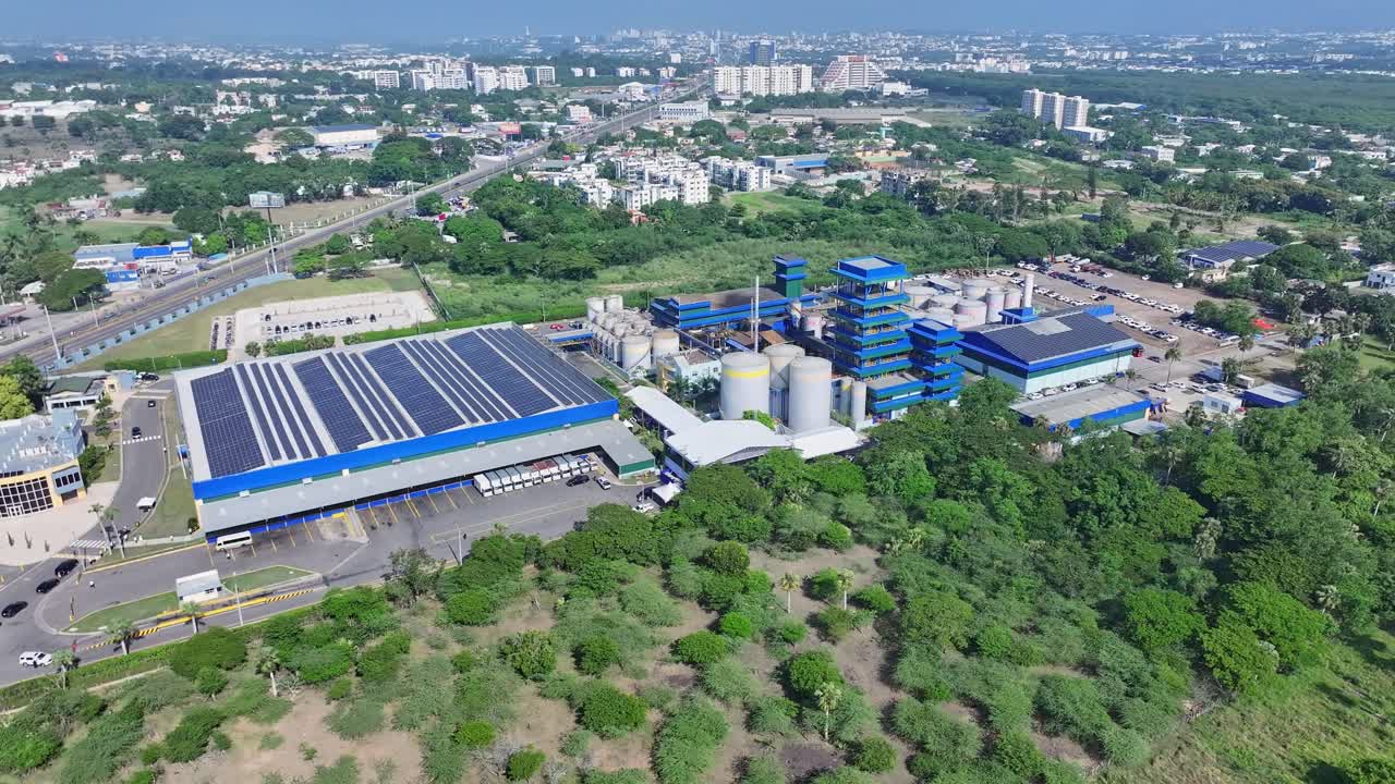 Aerial orbit modern blue factory in urban green city, solar panels and ...