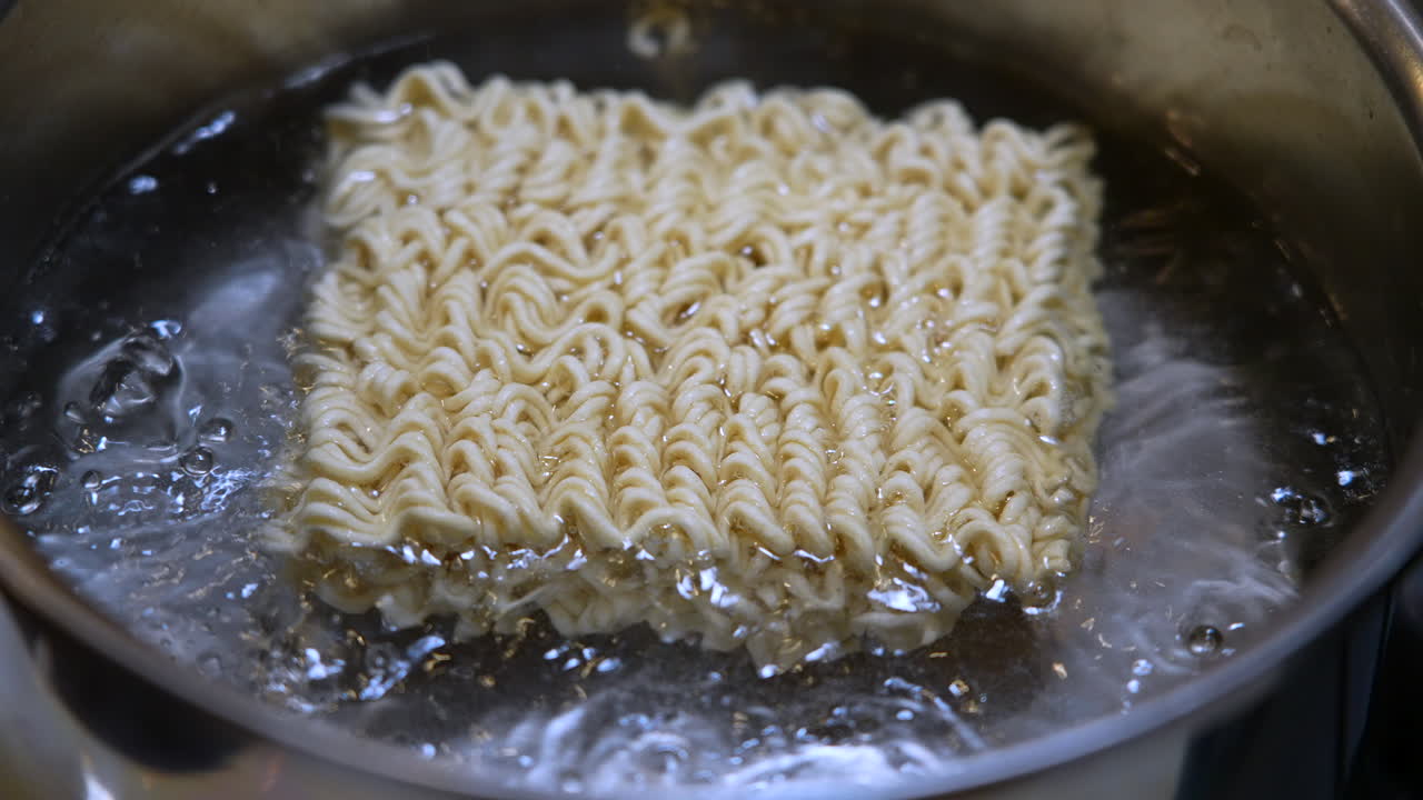 Premium stock video - Cooking ramen noodles in boiling water in a pot