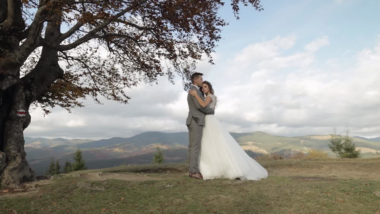 Lovely young newlyweds bride groom embracing on mountain autumn slope ...
