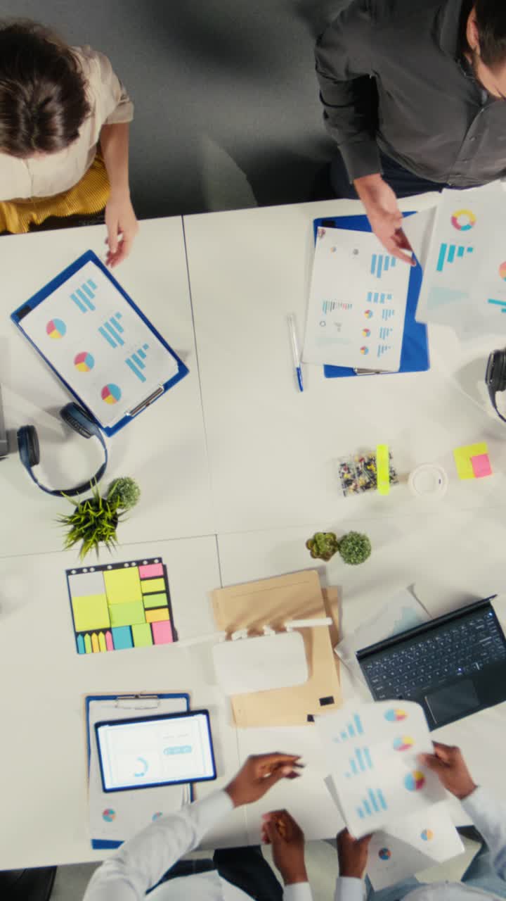 Vertical Video Top down view zoom out of professional staff analyzing ...