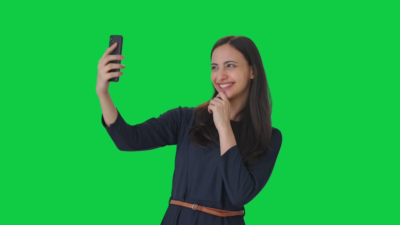 Happy indian girl clicking selfies green screen Premium Stock Video Footage