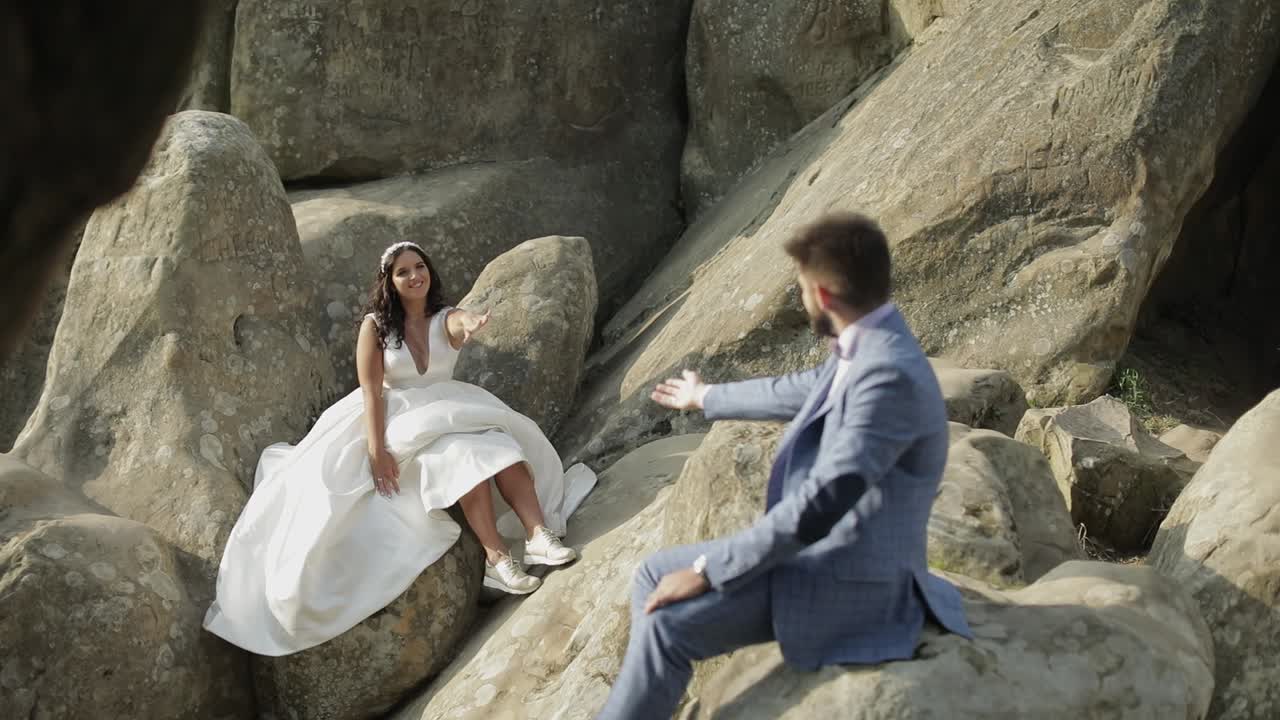 Groom with bride sit on a slope of the mountain. wedding couple. happy ...