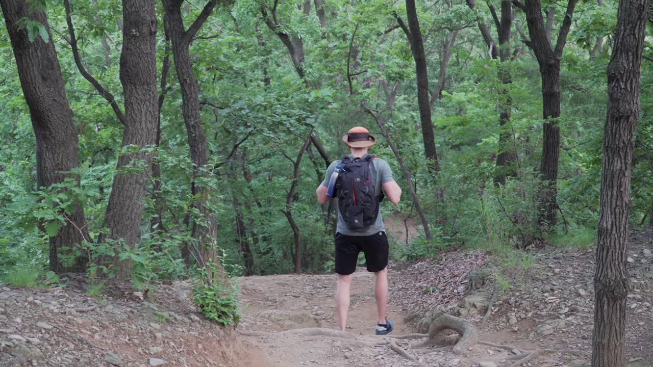 Premium stock video - Male hiker walking down the mountain hiking path ...