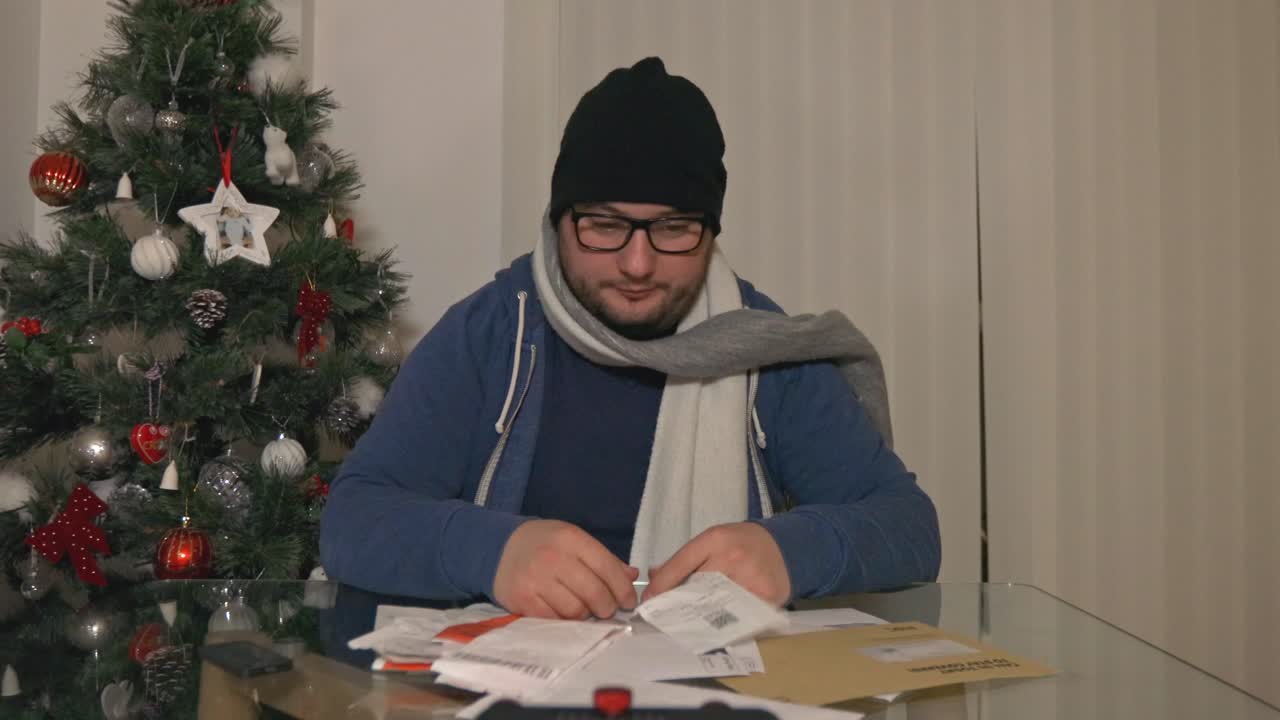 Frustrated hopeless man in winter clothes checking heap of bills to pay ...