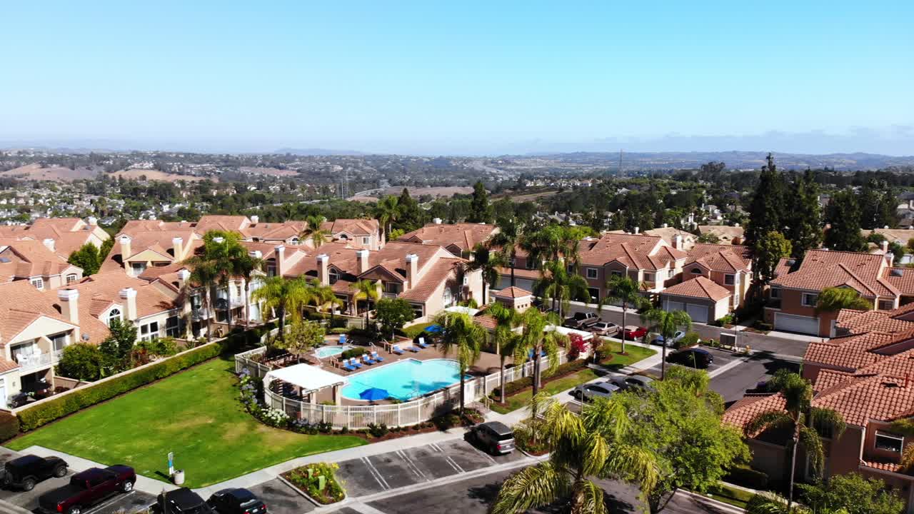 Aerial rotation over a condo complex pool panning to cityscape Premium ...