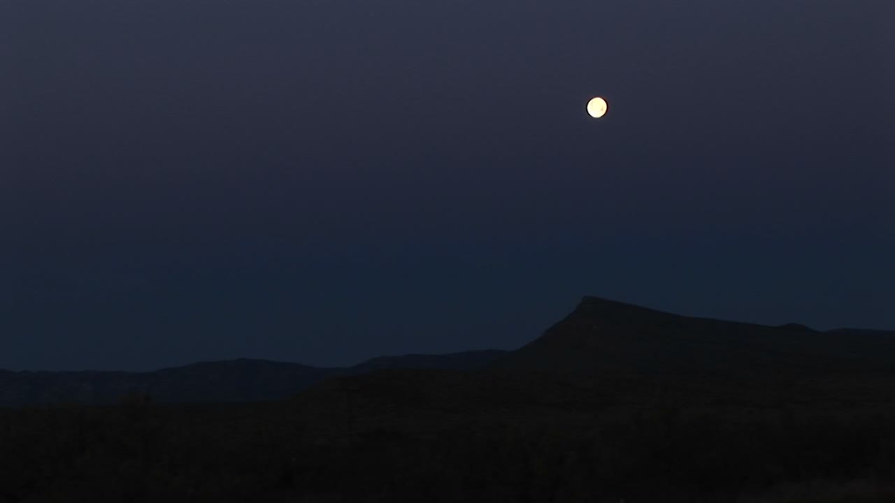 Longshot Of The Moon Over A Rocky Landscape | Premium Stock Video Footage