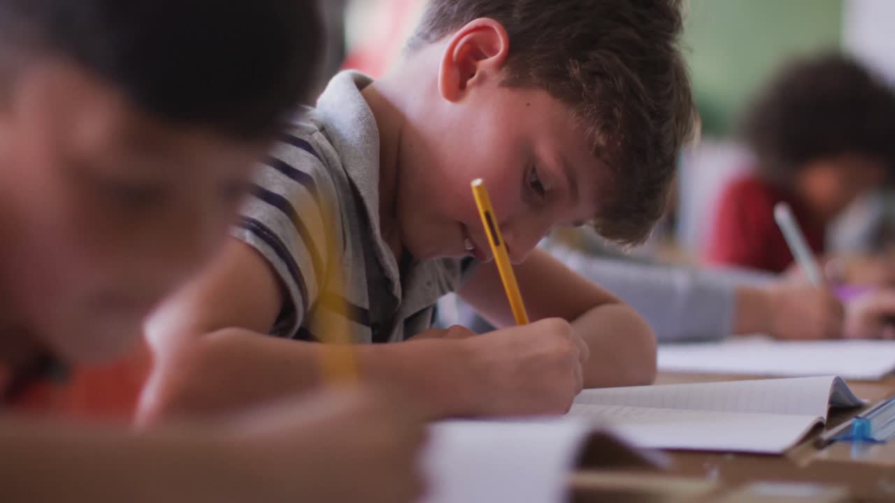 Two boys writing while sitting on their desk at school Premium Stock ...