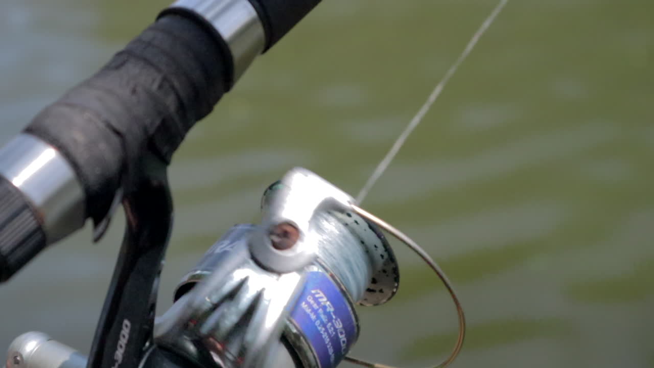 Premium stock video - Fisherman spinning reel on rod
