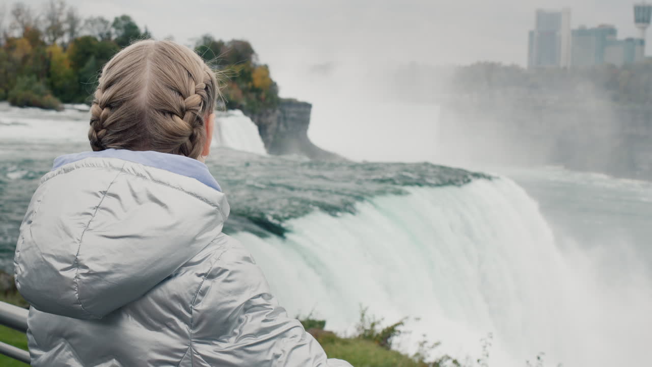 A child admires the spectacle of the niagara waterfall. stands close to ...
