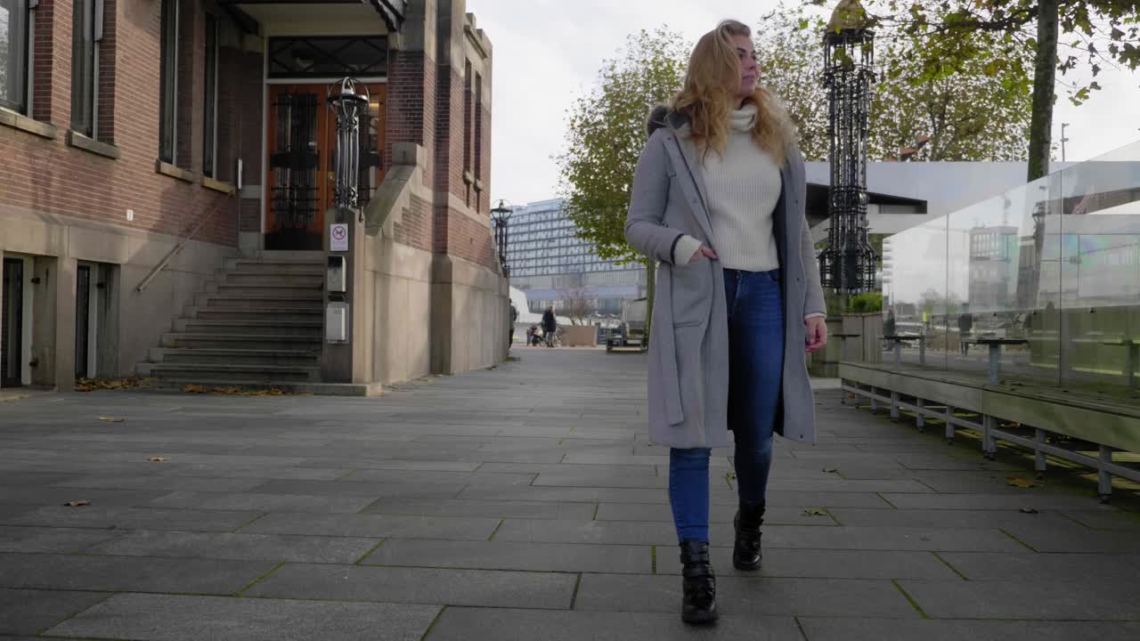 Premium stock video - Confident young blonde woman taking a stroll down ...