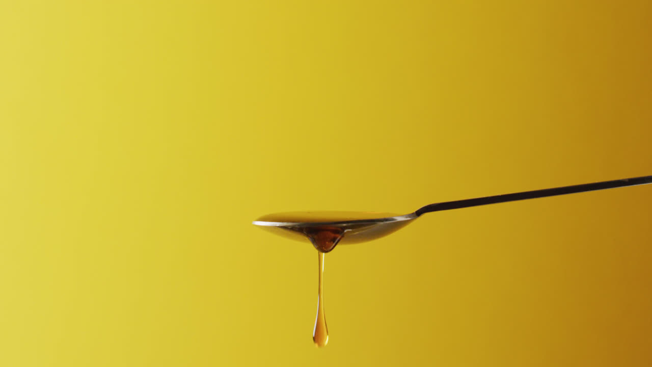 Premium stock video - Video of spoon with syrup on yellow background