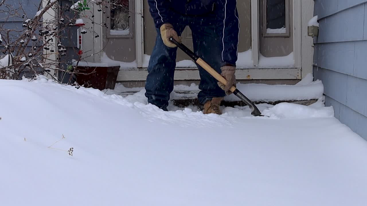 Premium stock video - Scooping snow to clear the front stoop after a ...