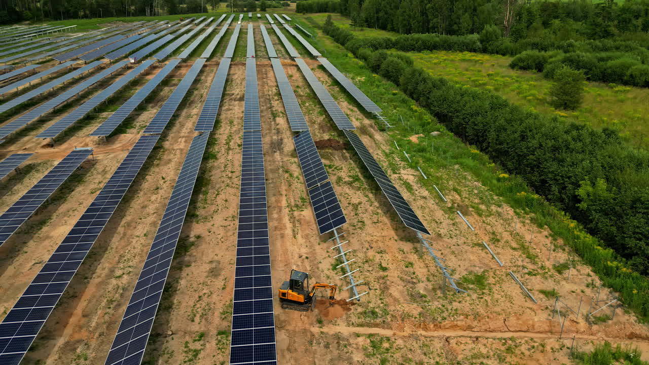 Vast arrays of solar panels on a solar farm, with an excavator ...