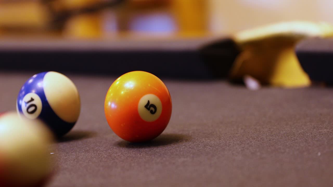 Premium stock video - Hitting balls into pockets on billiard table - close