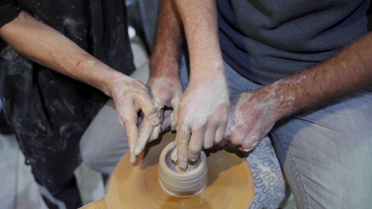 Two people shaping clay on a pottery wheel | Premium Stock Video Footage