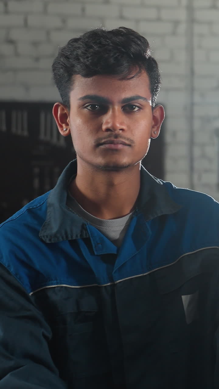 Inventor in blue uniform stands near car engine in automotive workshop ...