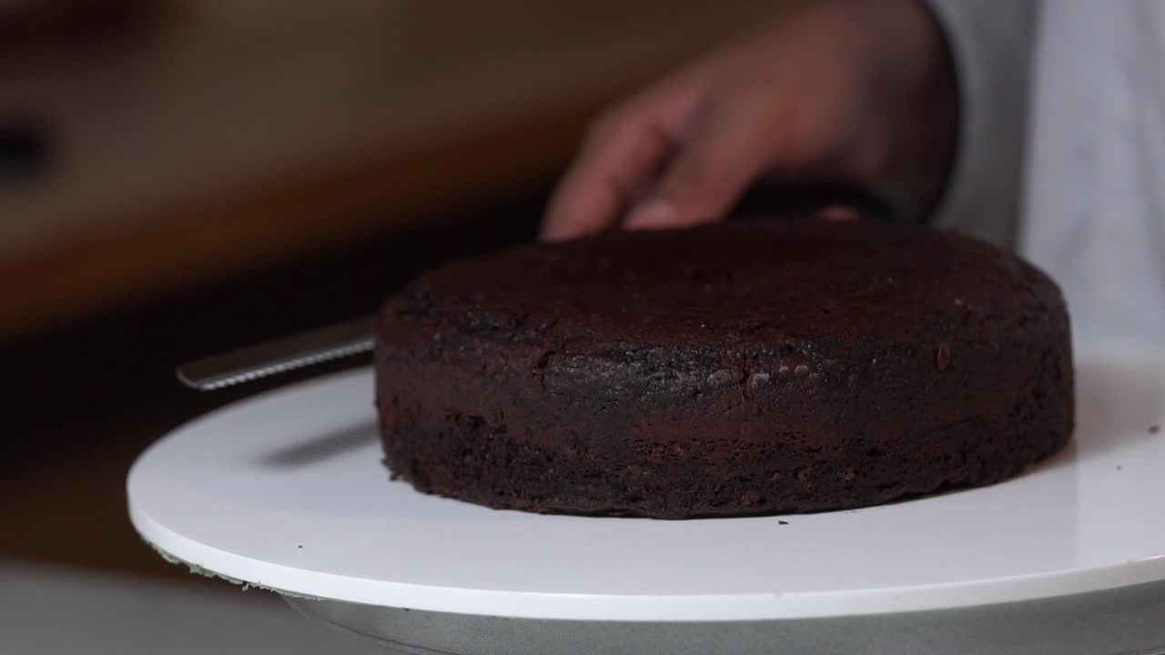 Premium stock video - Cutting baked cake in two layers for icing and design