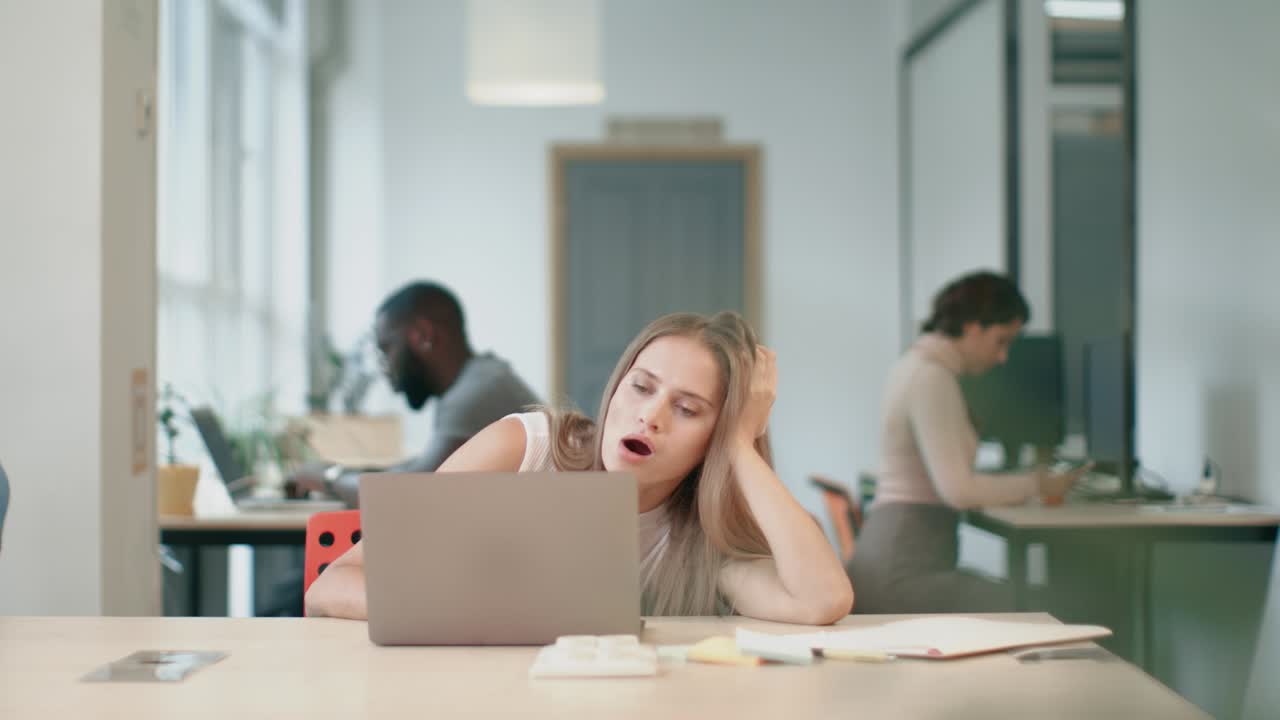 Young woman feeling sleepy at coworking. boring lady trying to work at ...