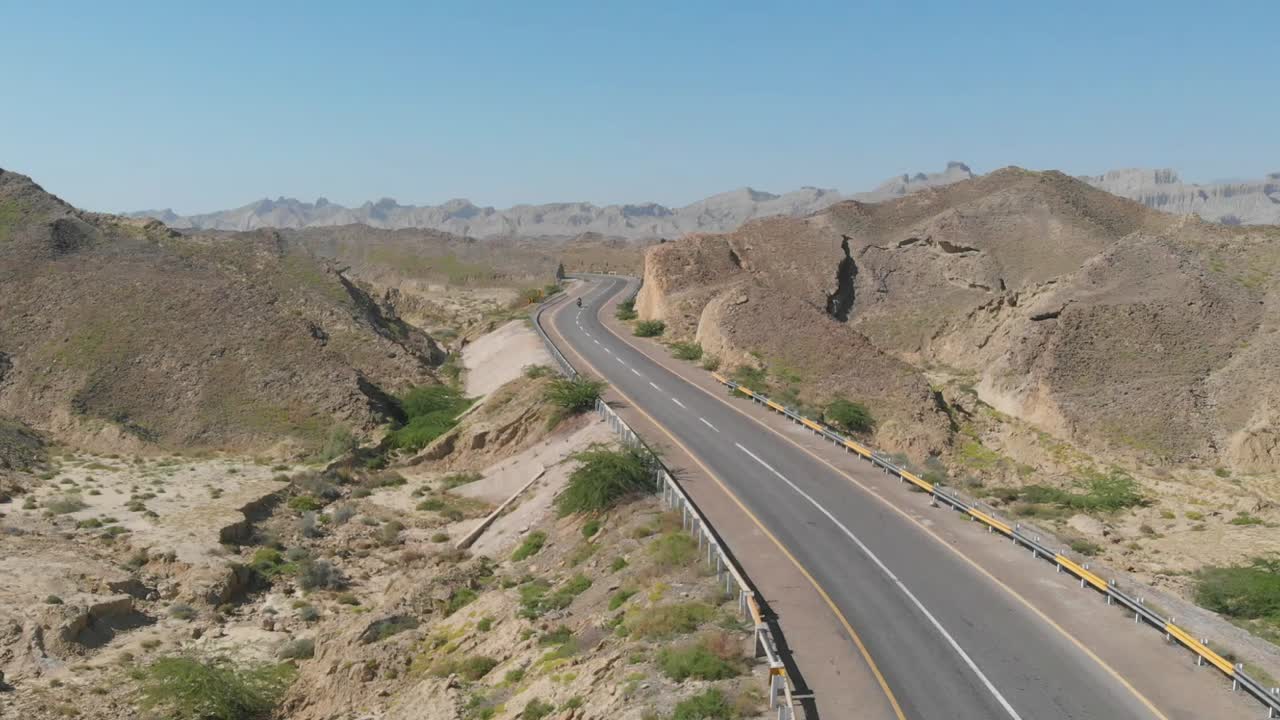 Aerial forward shot of beautiful empty coastal highway along pakistan's ...