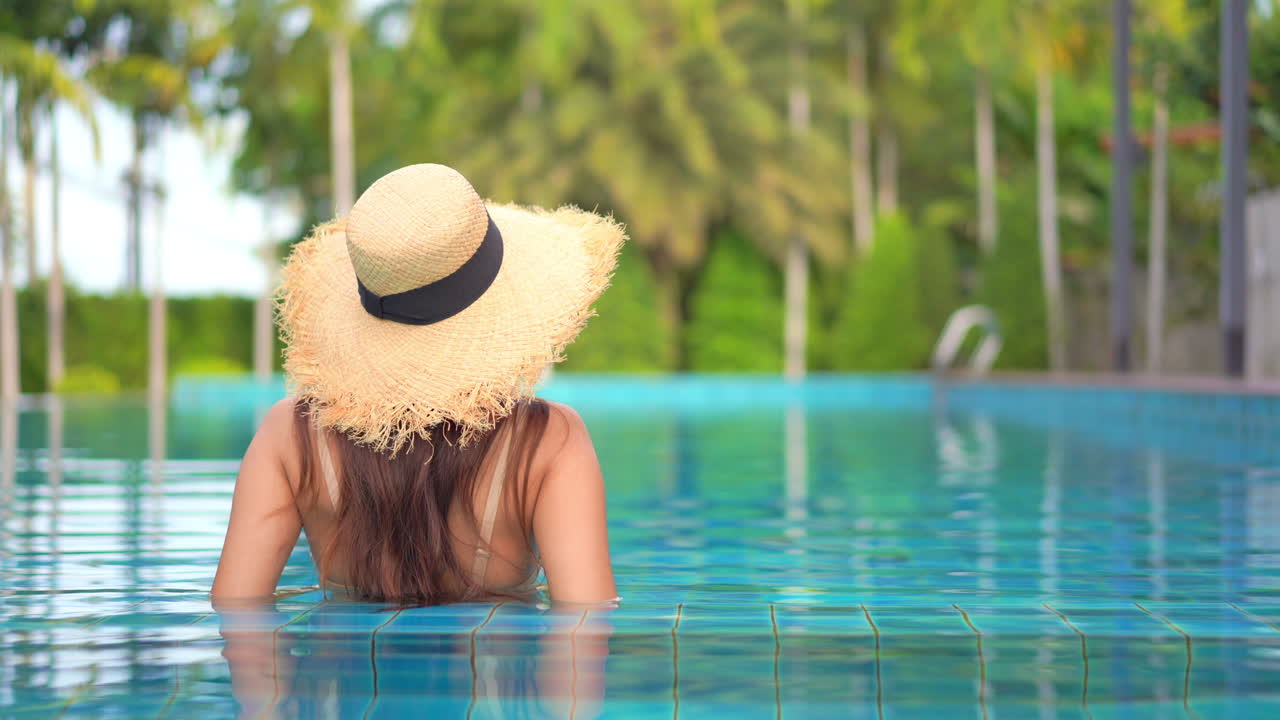 A Woman Wearing A Straw Hat, Relaxing In An Infinity Pool At A Luxury ...