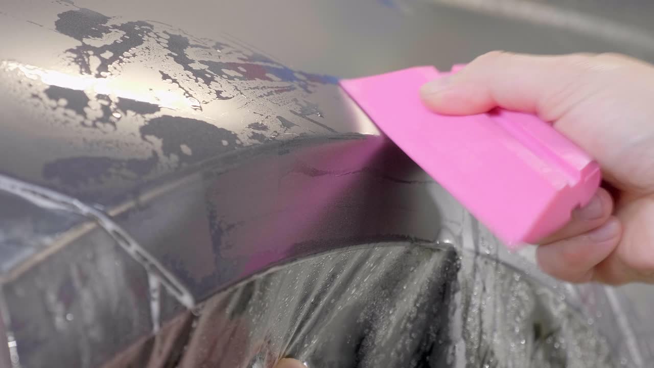 Free stock video - Specialist wrapping car with transparent foil close up