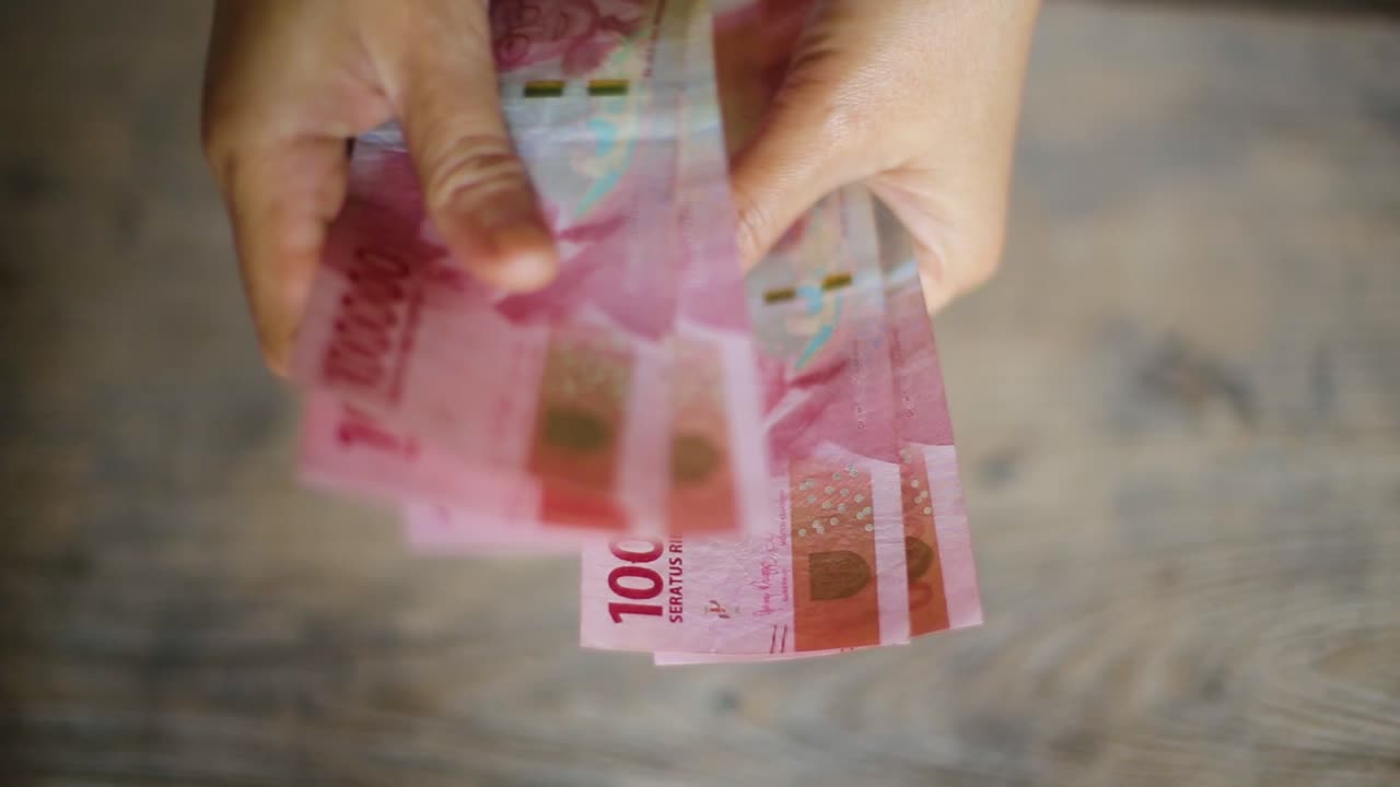 Premium stock video - Woman counts many rupiah red 100,000 banknotes in ...